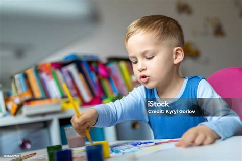 귀여운 금발의 소년의 초상화는 집이나 유치원 수업에서 수채화로 그림을 그리고 종이에 밝은 추상 이미지를 붓는 재미를 즐깁니다 상상력 발달 어린이 놀이 활동 2 3 살에 대한