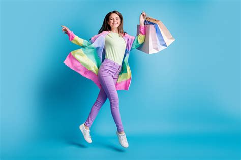 매력적인 포지티브 쇼핑객 점프 팔 플라잉 웨어 팬츠의 전신 사진은 파란색 배경에 고립 점프에 대한 스톡 사진 및 기타 이미지