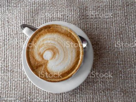 커피 카푸치노 또는 라떼를 접시가 있는 흰색 우아한 컵에 넣고 소박한 자루에 배경을 넣습니다 아침 뜨거운 음료 커피 라이프