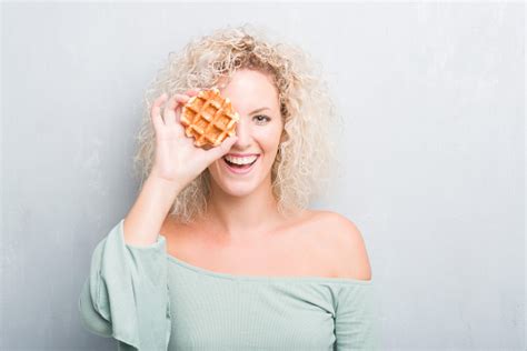 그런 지 회색 배경에 서 치아를 보여주는 자신감 미소로 웃 고 행복 한 얼굴로 벨기에 와플을 먹는 젊은 금발의 여 자가 곱슬 머리에 대한 스톡 사진 및 기타 이미지 Istock