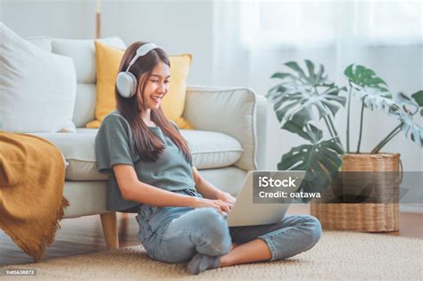 헤드폰을 끼고 집에서 소파 옆 양탄자에 앉아 노트북 웹 카메라를 사용하는 젊은 아시아 여성 가정 생활에 대한 스톡 사진 및 기타 이미지 가정 생활 거실 게으름