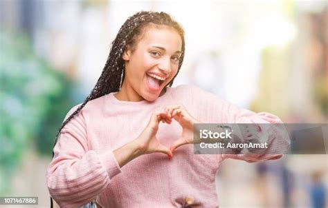 젊은 꼰된 머리 아프리카계 미국인 여자 마음 기호와 손으로 모양을 보여주는 사랑에 웃 고 고립 된 배경 위에 스웨터를 입고 낭만적인 개념입니다 손에 대한 스톡 사진 및 기타