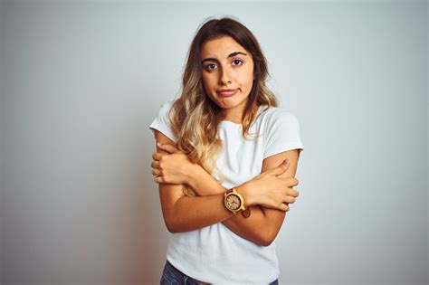 젊은 아름다운 여자는 얼굴에 슬프고 충격 표정으로 겨울 추위에 대한 고립 된 배경 흔들림과 동결 위에 캐주얼 흰색 티셔츠를 입고 T 셔츠에 대한 스톡 사진 및 기타 이미지