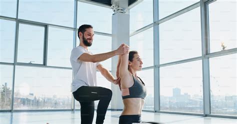 젊은 활동적인 여성이 체육관에서 훈련하는 동안 등을 위해 요가 운동을 하도록 돕는 전문 스포츠 트레이너 사진 Unsplash