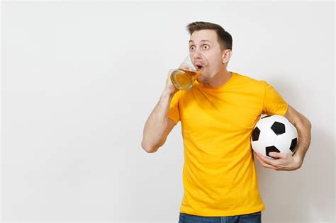 영감 을된 젊은 재미 쾌활 한 유럽 남자 팬 또는 노란색 유니폼에 선수 맥주 축구 볼 응원 좋아하는 축구 팀 흰색 배경에 고립의 파인트 찻잔 스포츠 놀이 라이프 스타일