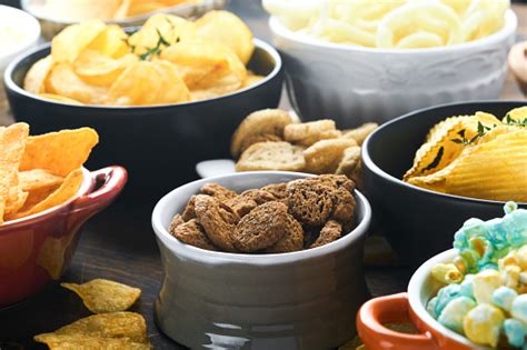 건강에 해로운 음식이나 간식 땅콩 팝콘 양파 반지와 소금에 절인 프레첼을 오래된 나무 배경의 그릇 접시에 담은 모든 고전적인 감자 스낵 인물 심장 피부 치아에 대한 건강에