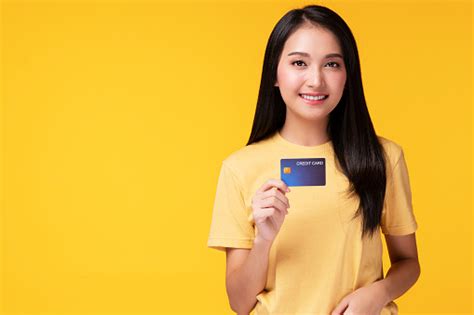 고립된 흰색 배경 위에 빈 카피 공간을 보면서 손과 신용 카드 모형을 들고 캐주얼 한 옷을 입은 쾌활한 젊은 여성 지불 구매 및 금융 개념 25 29세에 대한 스톡 사진 및