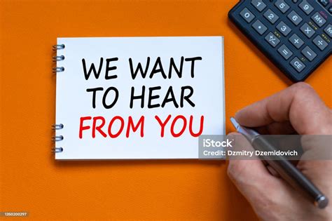 기호를 지원합니다 사업가는 흰색 노트에 우리는 당신에게서 듣고 싶다라는 단어를 쓰고 있습니다 검은 계산기 아름다운 오렌지 배경