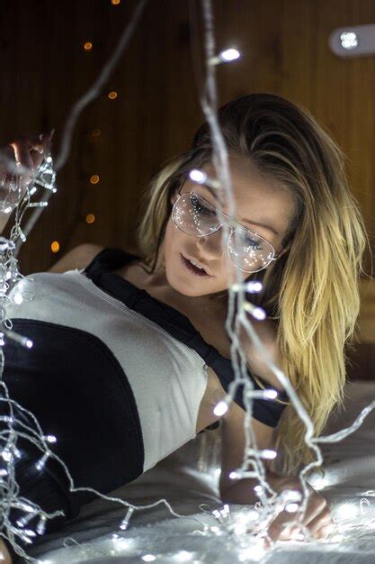 Premium Photo Close Up Of Woman With Illuminated String Light Lying On Bed