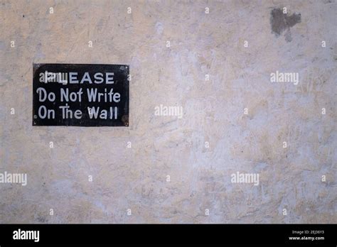 A Black Warning Signboard Saying Please Do Not Write On The Wall In