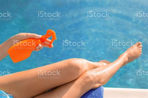 여름철 수영장 근처의 여성 슬림 다리에 적용 하는 화장품 선 스크린 제품입니다 여성 손에 자외선 차단 바디 크림의 오렌지 병