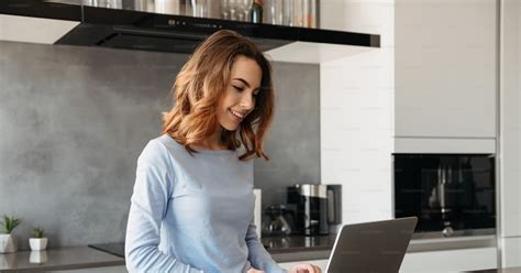 집에서 식탁에 서 있는 동안 노트북 컴퓨터를 사용하는 즐거운 젊은 여성의 초상화 사진 Unsplash의 랩톱 이미지