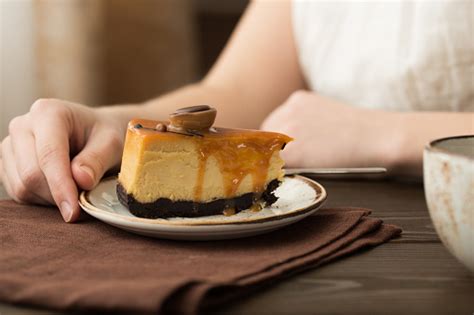 갈색 배경에 소금에 절인 캐러멜치즈케이크로 차를 마시는 여성 텍스트공간을 복사합니다 접시에 비건 코코넛 치즈 케이크의 조각 과일에 대한 스톡 사진 및 기타 이미지 Istock