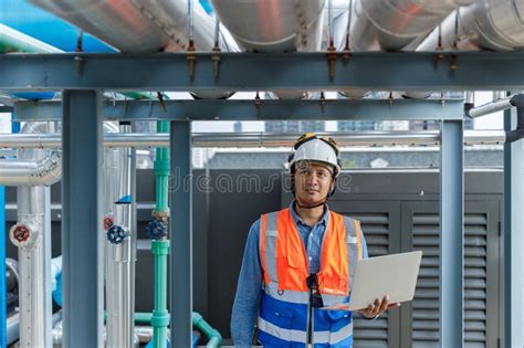 Asian Man Engineer Using Laptop Checking Valve Working At Rooftop Building Construction