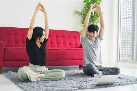 젊은 아시아 부부는 미소와 행복한 벌채 집에서 거실에서 빨간 소파 근처 바닥에 운동하는 남자와 여자 운동을 사랑해요 코로나