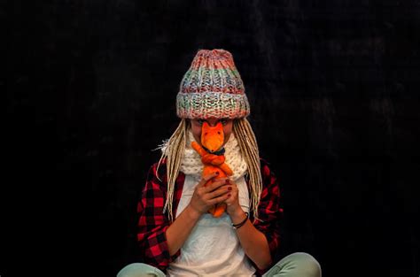 따뜻한 겨울 니트 모자와 스카프를 입은 공포와 빨간 격자 무늬 셔츠를 입은 아름다운 어린 소녀가 얼굴 근처에 부드러운 여우