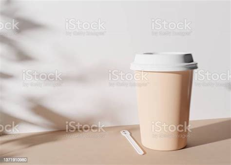 플라스틱 뚜껑이 있는 밝은 갈색 골판지 커피 컵이 모의 것입니다 디자인 광고 로고를 위한 빈 템플릿입니다 공간을 복사합니다 식물의 그림자크림 배경에 컵 프리젠 테이션 3d