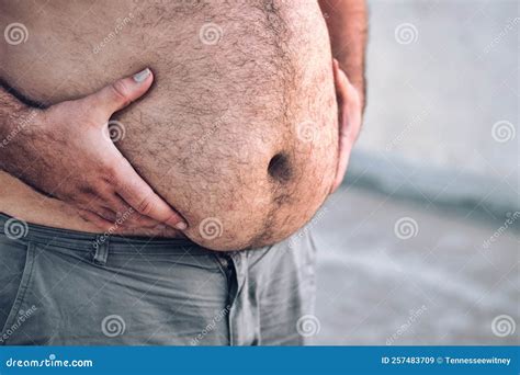 Close Up Of A Grown Man`s Round And Full Hairy Belly With Both Hands