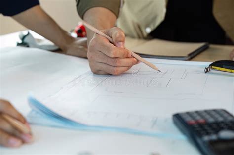 Architect Engineer Working On Blueprint With Pencil And Calculator On Desk Close Up Of Hands