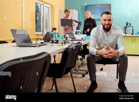 A Man Sitting In A Robotics Laboratory While His Colleagues In The Background Test New Cutting