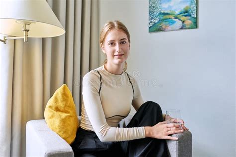 улыбающаяся девочка подросток сидя в кресле дома расслабленно смотрит в камеру Стоковое Фото