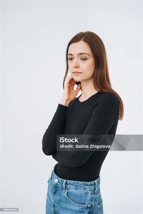 검은 긴 소매와 흰색 배경에 전체 길이의 청바지에 어두운 긴 머리를 가진 젊은 아름다운 여성을 생각하는 수직 초상화 30 34세에 대한 스톡 사진 및 기타 이미지 Istock