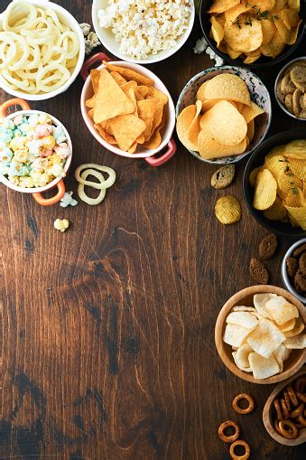 건강에 해로운 음식이나 간식 땅콩 팝콘 양파 반지와 소금에 절인 프레첼을 오래된 나무 배경의 그릇 접시에 담은 모든 고전적인 감자 스낵 인물 심장 피부 치아에 대한 건강에