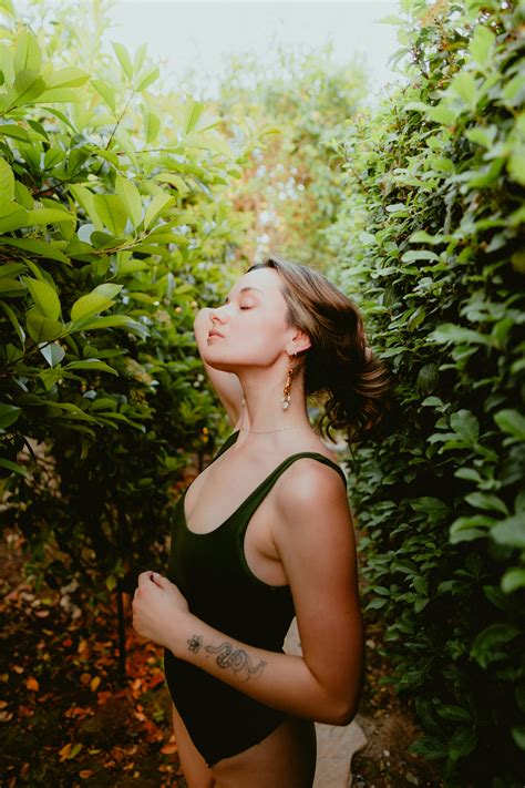 A Woman In A Black Bathing Suit Standing In Front Of A Bush Photo