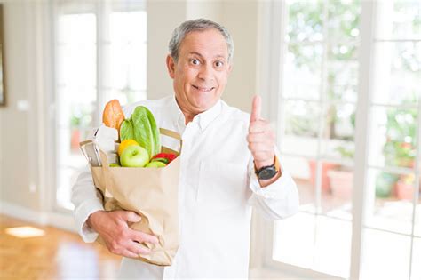 잘 생긴 노인 은 슈퍼마켓에서 신선한 식료품의 종이 가방을 들고 큰 미소와 함께 행복 확인 기호 손가락으로 엄지 손가락 우수한 기호 가득 찬에 대한 스톡 사진 및 기타