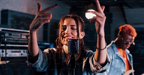 남자는 기타를 연주하고 여자는 노래합니다 백인 소녀와 함께 스튜디오에서 리허설을 하는 아프리카계 미국인 남자 사진 Unsplash의 공생 이미지