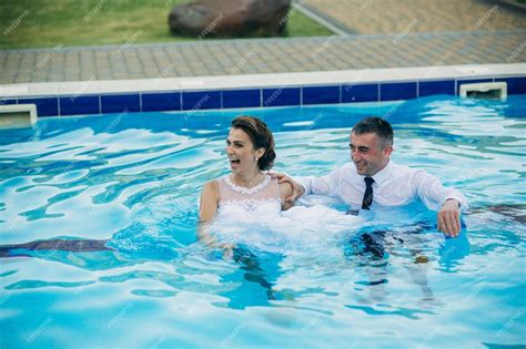 Young Couple Jumping In The Swimming Pool In A Wedding Suit And Wedding