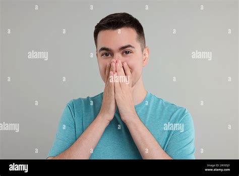 Embarrassed Man Covering Mouth With Hands On Grey Background Stock