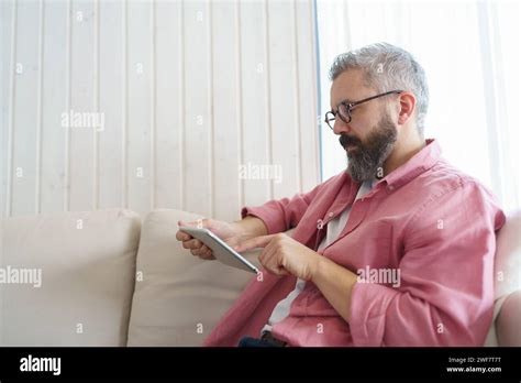 Man Using Smart Thermostat Adjusting Lowering Heating Temperature At Home Man Watching Tv