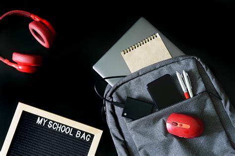 검은 배경에 노트북 Ssd 드라이브 휴대 전화 헤드폰 마우스 펜 및 메모장이있는 회색 도시 배낭 가제트의 개념과 현대 학교 소년 또는 학생의 가방 0명에 대한 스톡 사진 및
