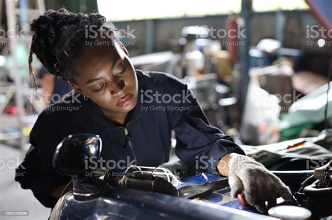 제복을 입은 여성 기술자 자동차 정비사가 정비소에서 정비를 점검하고 있다 자동차 엔진의 엔진 오일 레벨을 확인하는 작업자 자동차 센터 수리 서비스의 개념입니다 20 24세에