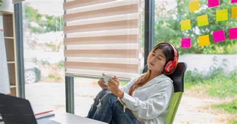 헤드폰으로 음악을 듣고 노트북 컴퓨터를 사용하고 사무실에서 커피를 마시는 젊은 아시아 여성의 초상화 사진 Unsplash의 홈 오피스 이미지