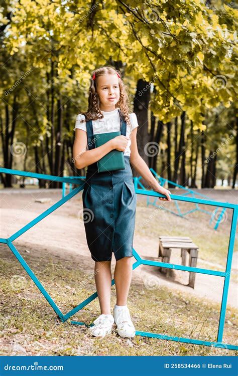 Une étudiante En Uniforme Scolaire Avec Un Livre Se Tient Dans Le Parc