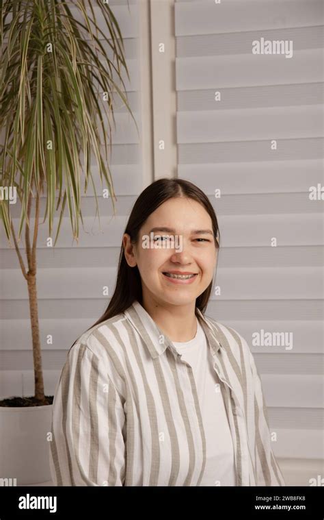 Smiling Woman With Braces Looking At Camera In Room With White Closed Blinds On Window Stock