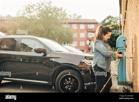 Side View Of Mid Adult Woman Plugging In Cable At Station Stock Photo Alamy