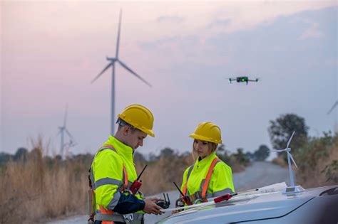 엔지니어는 제복을 입고 청사진 문서 검사 작업을 읽고 풍력 터빈 농장에서 전기로 회전하고 자동차 모델 풍차와 풍력 측정기 앞에 서서 생태 에너지 개념입니다 20 24세에