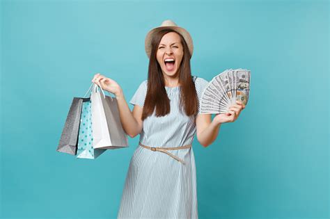 여름 복장 쇼핑 후 구매와 패키지 가방을 들고 밀 짚 모자에에서 세로 젊은 여자 많은 달러 지폐 현금 돈 파란색 배경에 고립