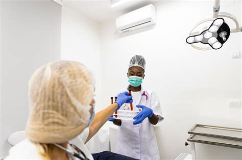 적절한 장비와 보호 마스크를 가진 두 명의 의사가 코로나바이러스 스톡 사진에 대해 환자를 검사합니다 2명에 대한 스톡 사진 및