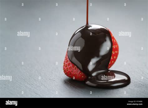 Pouring Chcolate Sauce On Fresh Ripe Strawberry On Slate Background