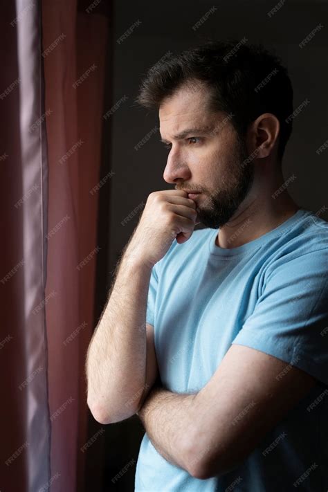 Вид сбоку встревоженный мужчина смотрит в окно Бесплатно Фото