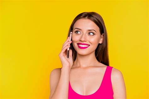 외딴 밝은 배경을 만나는 것에 대해 이야기하는 친구에게 전화를 걸고 귀 근처에 스마트 폰을 들고 사용하는 사랑스럽고 아름다운