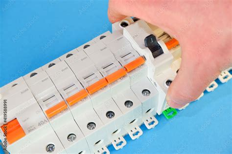 Automatic Differential Current Switch And Circuit Breakers On A Blue Background A Man S Hand
