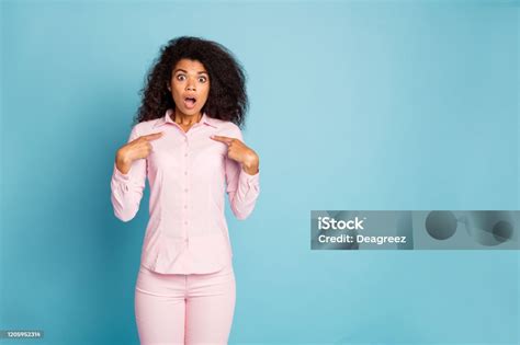 자신에게 손가락을 나타내는 말도 어두운 피부 물결 모양의 아가씨의 사진은 그녀가 돈 복권의 승자라고 생각하지 않습니다 핑크 셔츠 바지 고립 된 파란색 배경 가리키기에 대한
