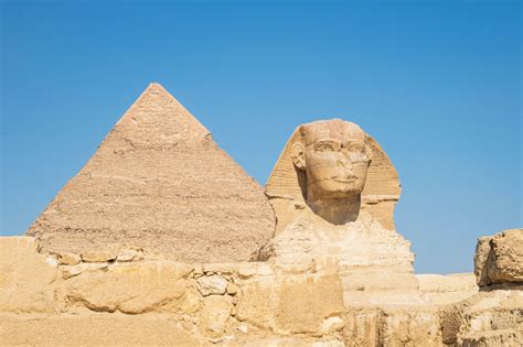 A Closeup Of The Face Of The Great Sphinx With Pyramid In The Background On A Beautiful Blue Sky