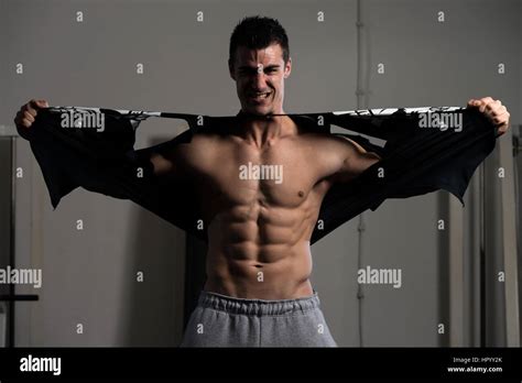 Handsome Man Standing Strong In The Gym And Ripping The T Shirt Off Muscular Athletic