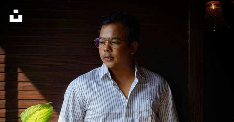 흰색과 파란색 줄무늬 드레스 셔츠를 입은 남자가 녹색 식물 옆에 서 있다 사진 Unsplash의 무료 사람의 이미지